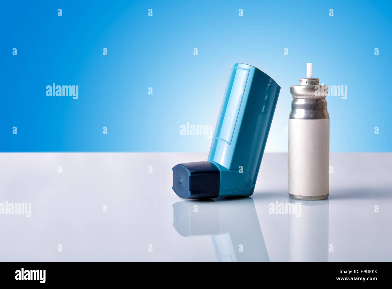 Cartridge and blue medicine inhaler on white glass table with blue ...