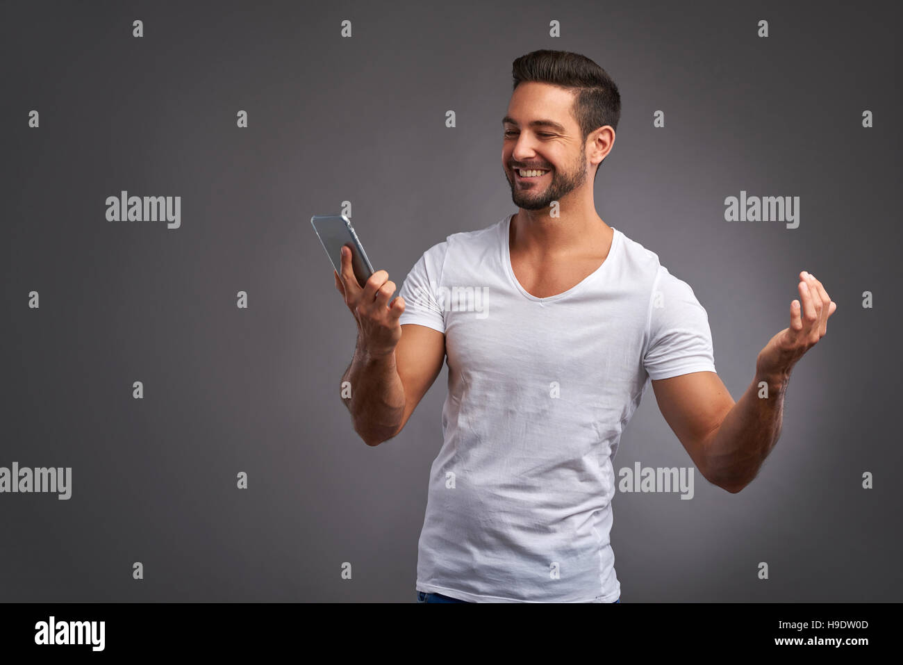 A handsome young man holding his phone and celebrating Stock Photo - Alamy