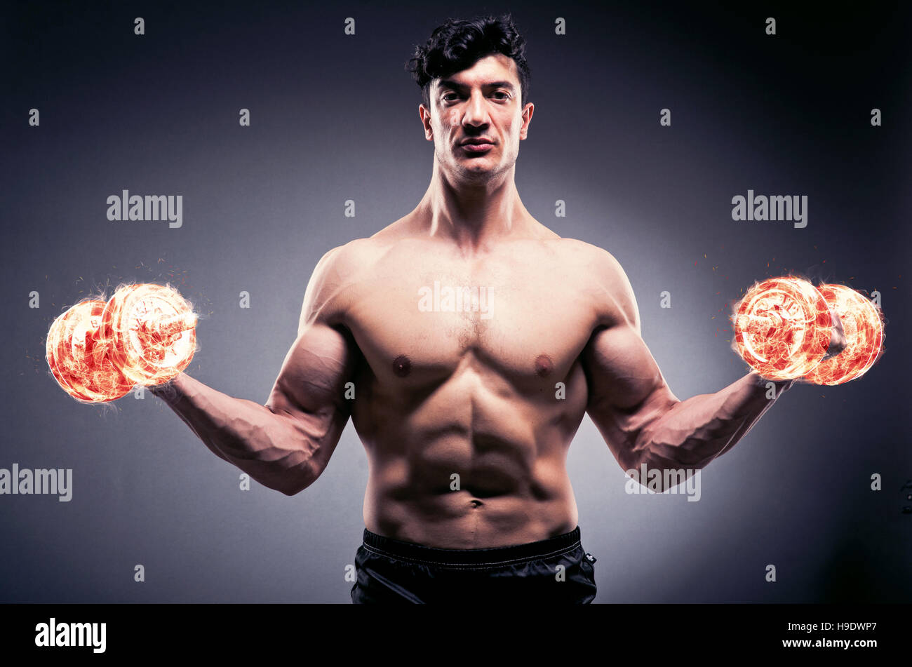 Muscular ripped bodybuilder with burning dumbbells Stock Photo - Alamy