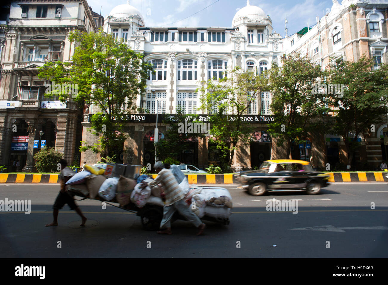A man powered cart walks past Victorian era buildings in central Mumbai ...