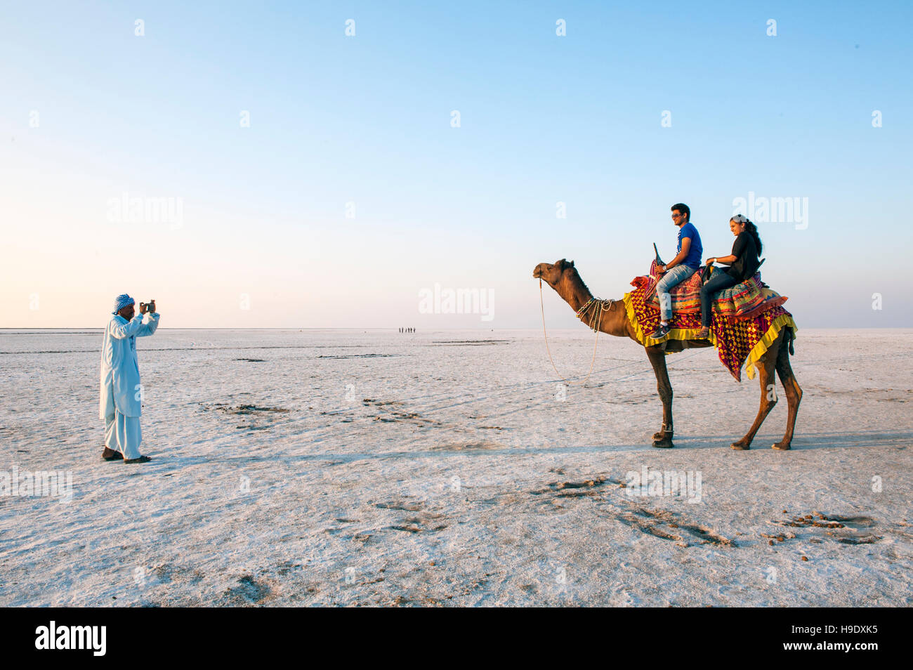 A local guide photographing tourists on a camel in the Great Rann of ...