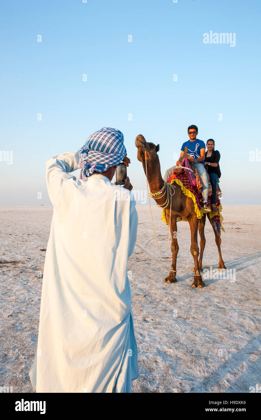 A local guide photographing tourists on a camel in the Great Rann of ...