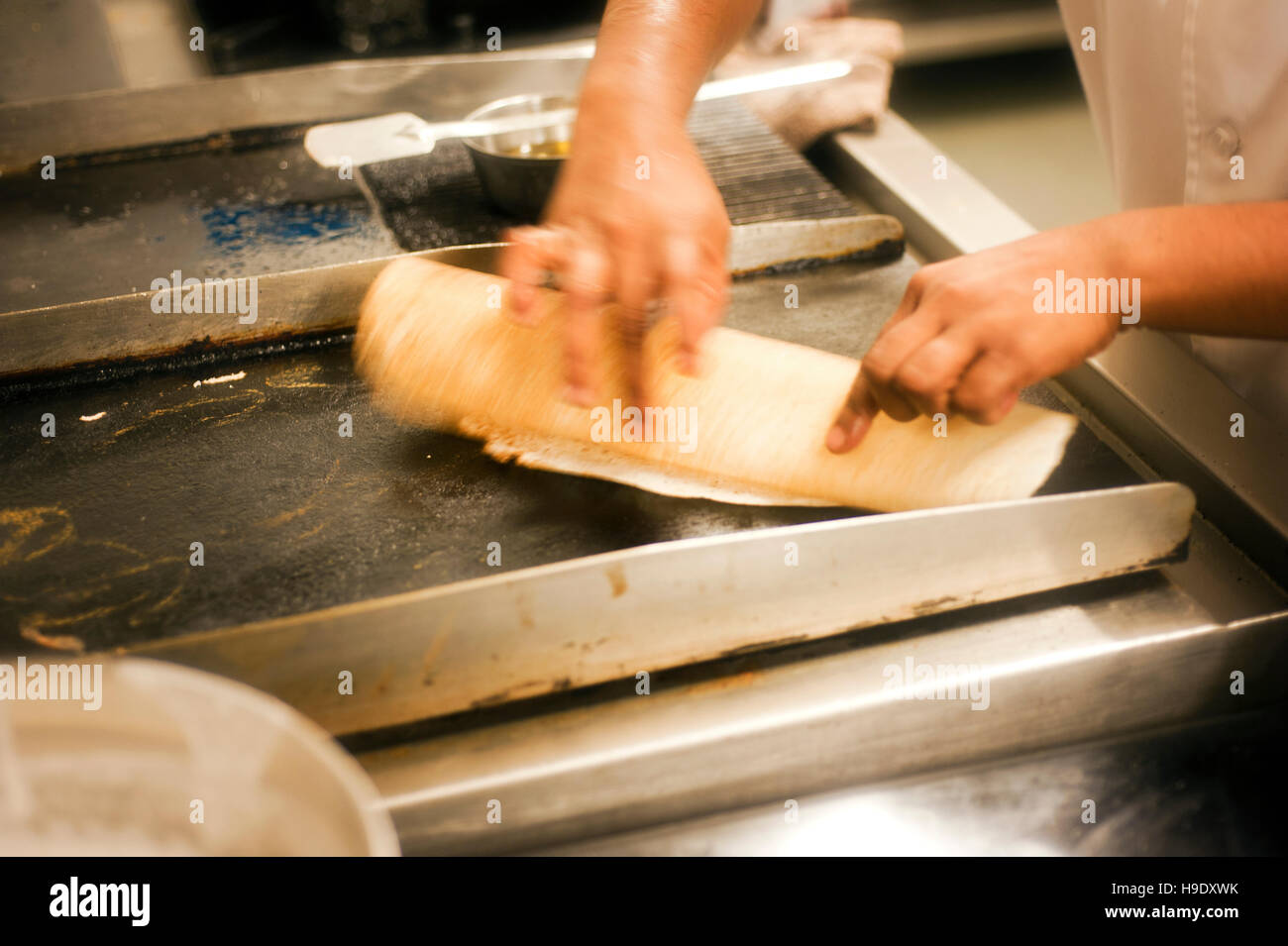 A cook preparing dosa, a pancake of fermented rice and black lentils ...