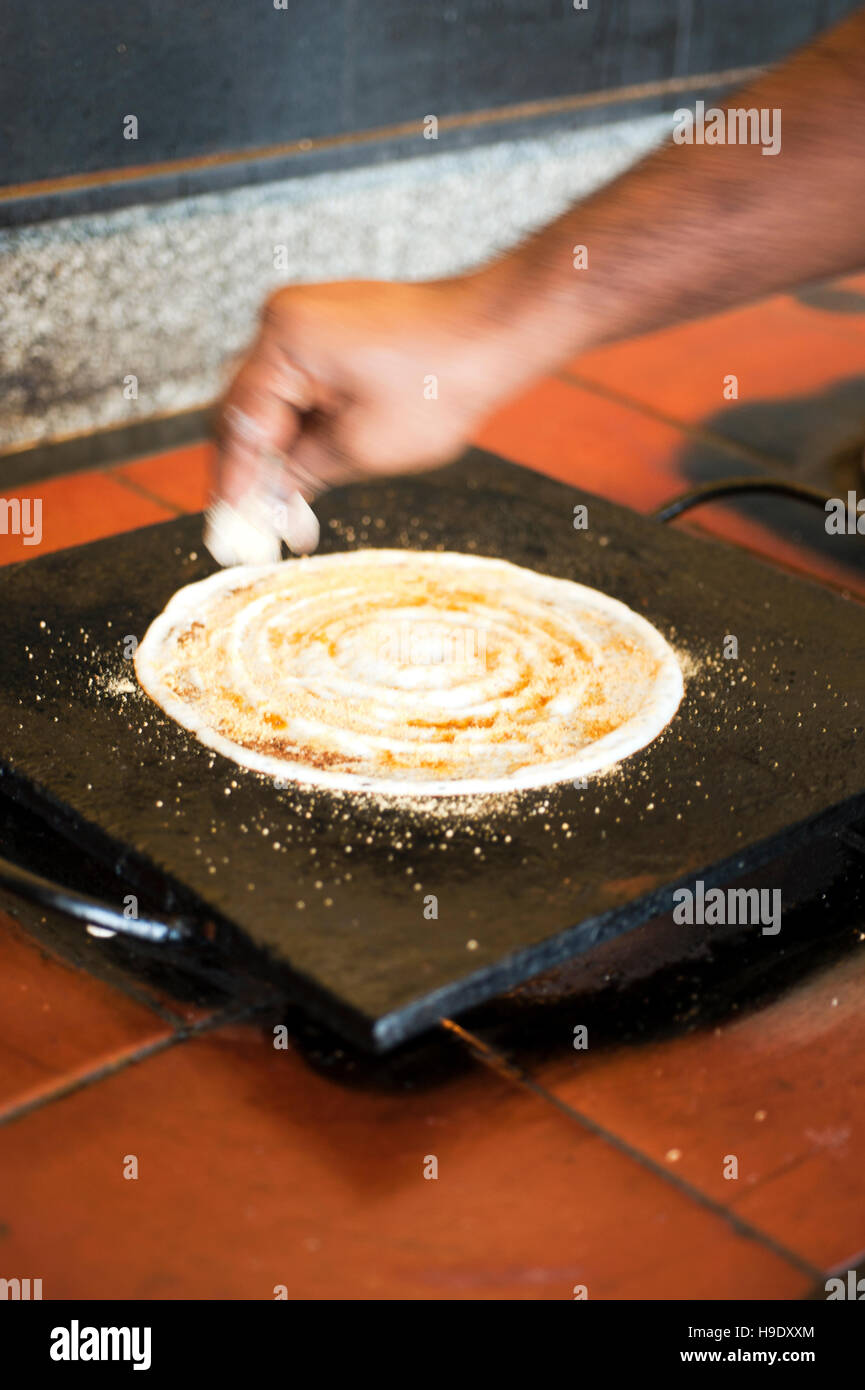 Preparing dosa, a pancake of fermented rice and black lentils, with egg ...