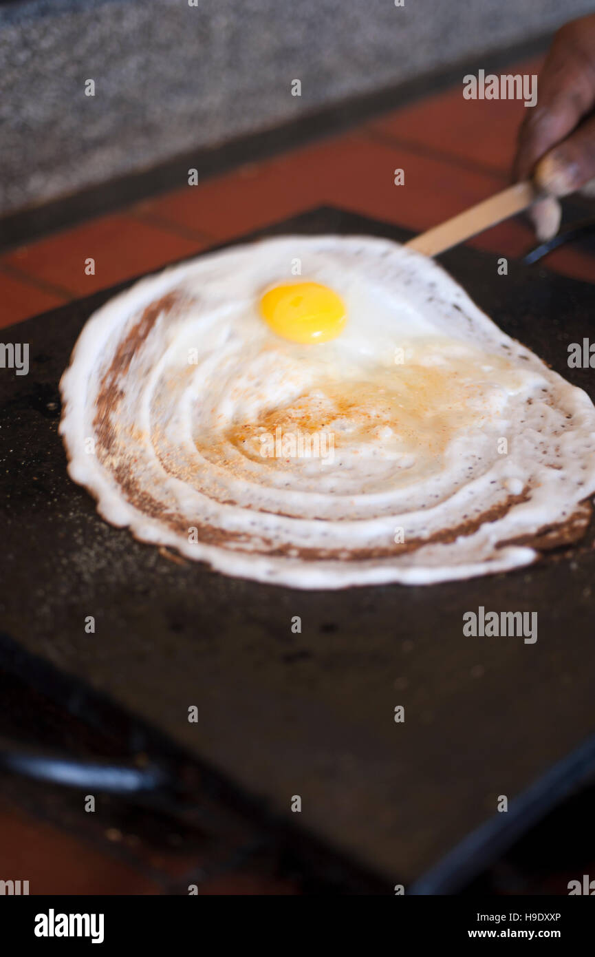 Preparing dosa, a pancake of fermented rice and black lentils, with egg ...