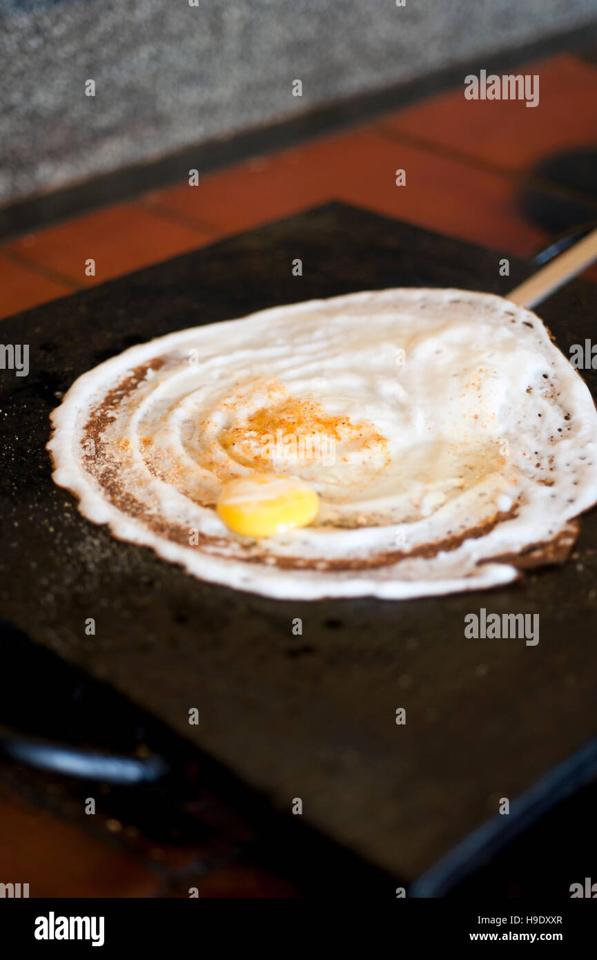 A cook preparing dosa, a pancake of fermented rice and black lentils ...