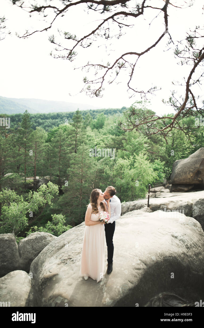 Wedding couple in love kissing and hugging near rocks on beautiful ...