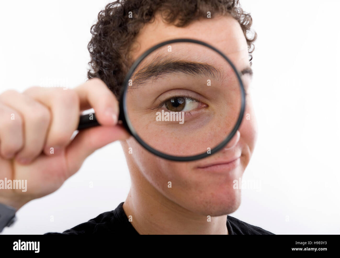 Young man looking through a magnifying glass Stock Photo - Alamy