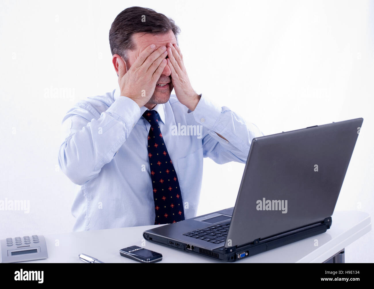 Desperate businessman, over 50, working on a laptop Stock Photo - Alamy