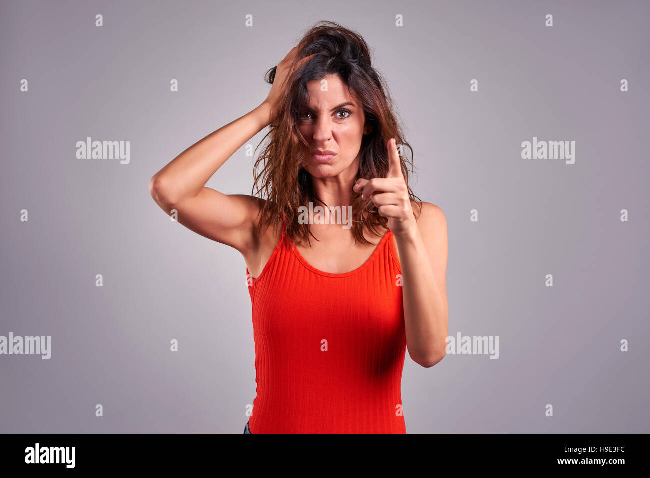 A beautiful young woman looking angry and warning with her hand in a ...