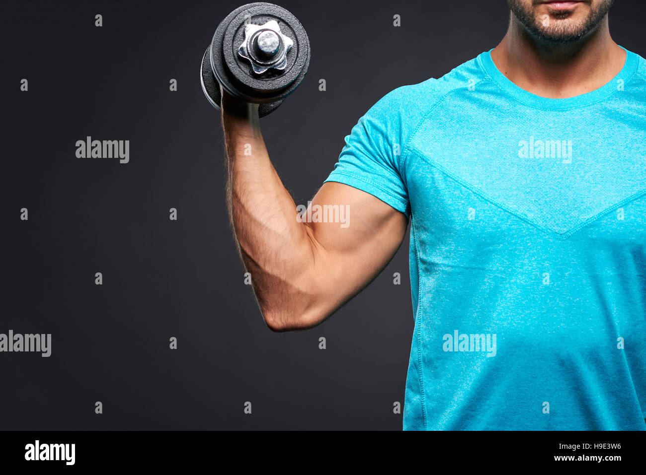A closeup look of a young sportsman lifting a dumbbell with one hand ...