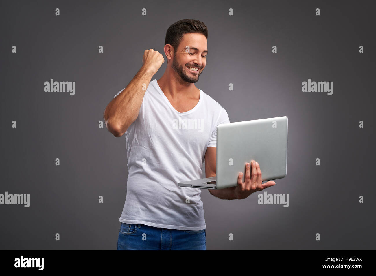 A happy handsome young man holding a laptop and celebrating Stock Photo ...