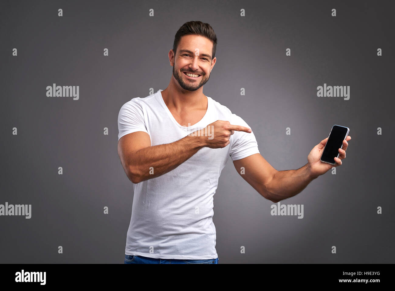 A confident handsome young man showing his phone to the camera and ...