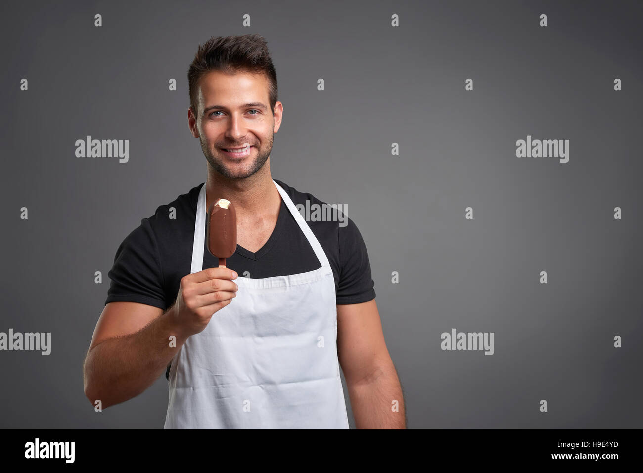 A handsome young barista man smiling and enjoying an ice-cream Stock ...