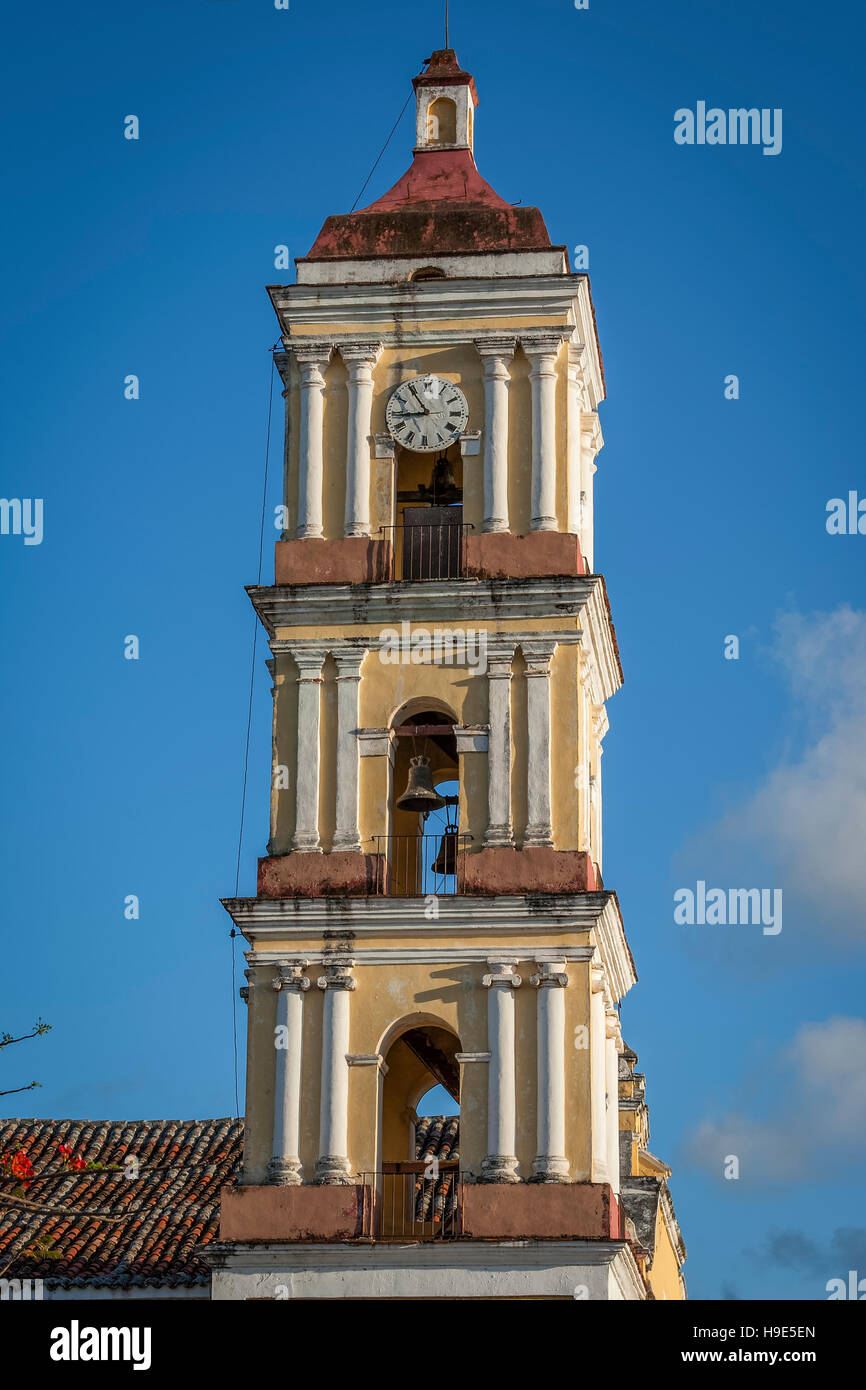 Tall yellow tower of a building in the middle of Cuba with a clock face ...