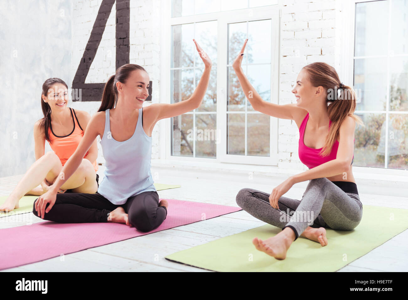 Three young girls giving high five in fitness studio Stock Photo - Alamy