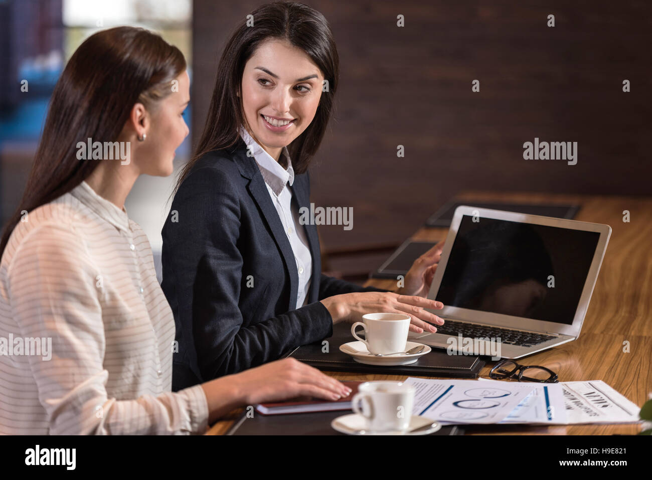 Female colleagues using laptop in an office Stock Photo - Alamy
