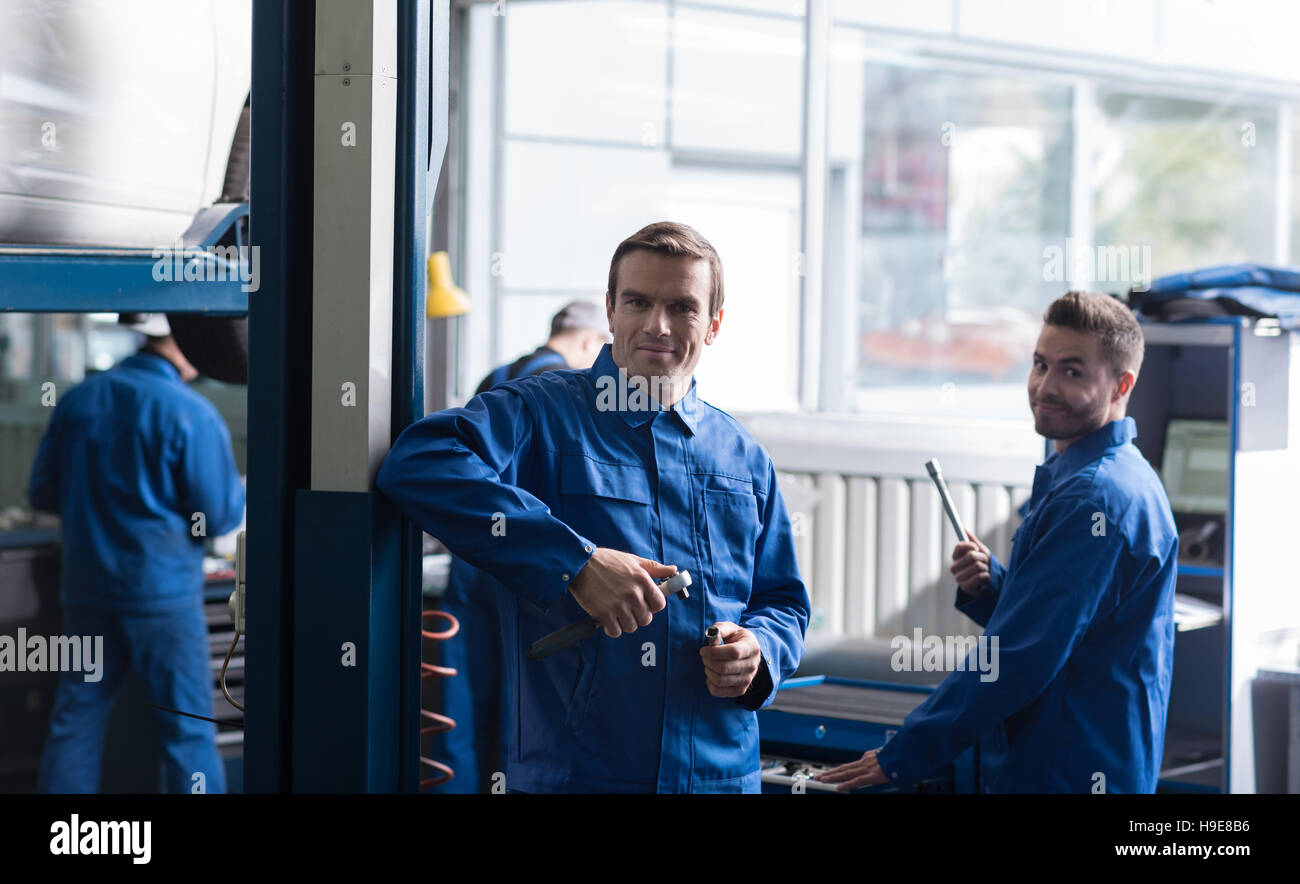 Cheerful auto mechanics holding tools Stock Photo - Alamy