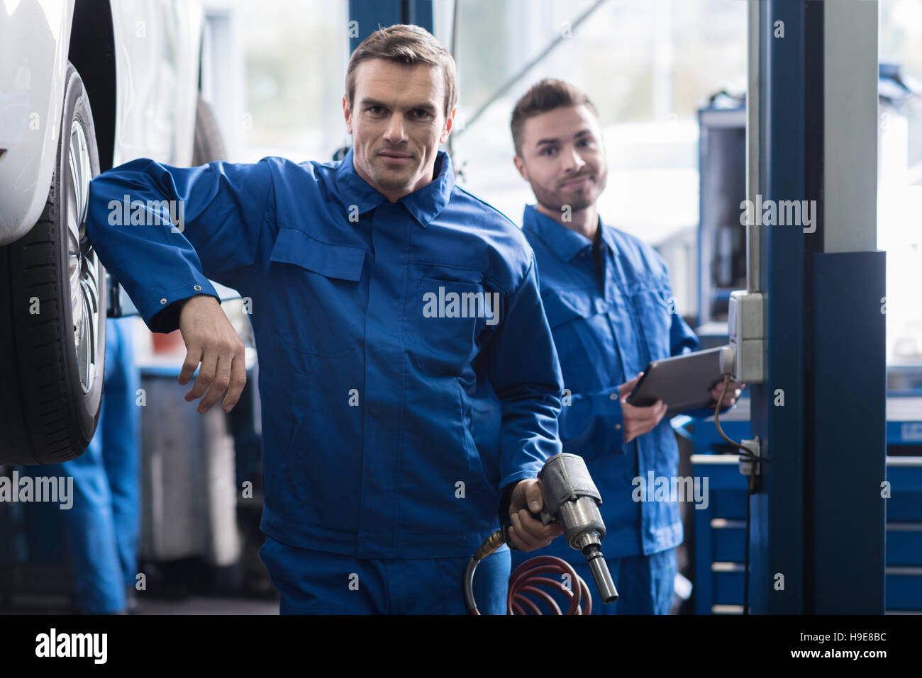 Professional car mechanic uwing pneumatic wrench Stock Photo - Alamy