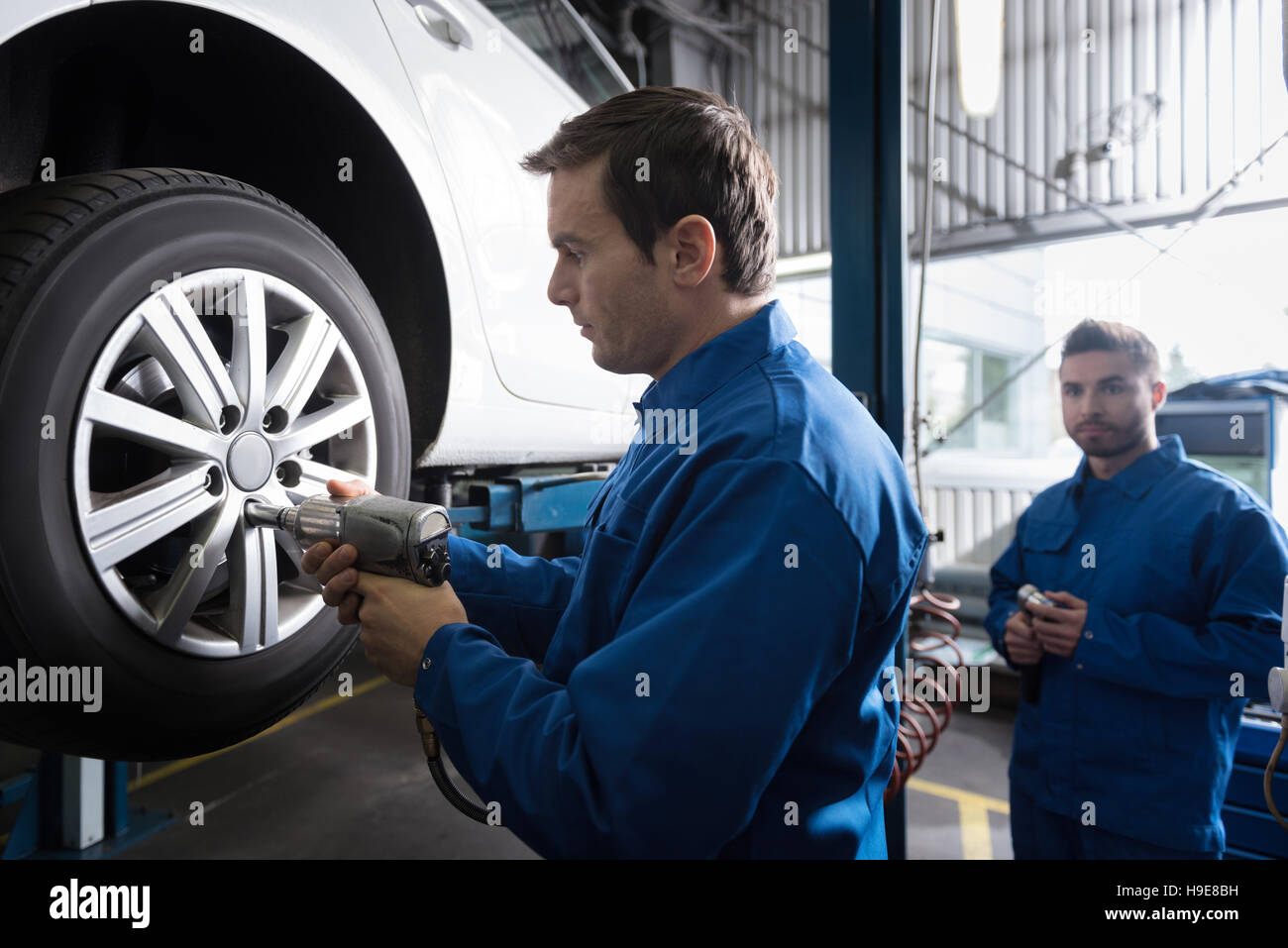 Pleasant mechanic changing car wheel Stock Photo - Alamy
