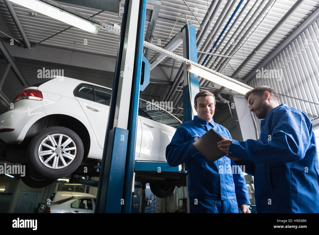Positive mechanics working in auto service Stock Photo - Alamy