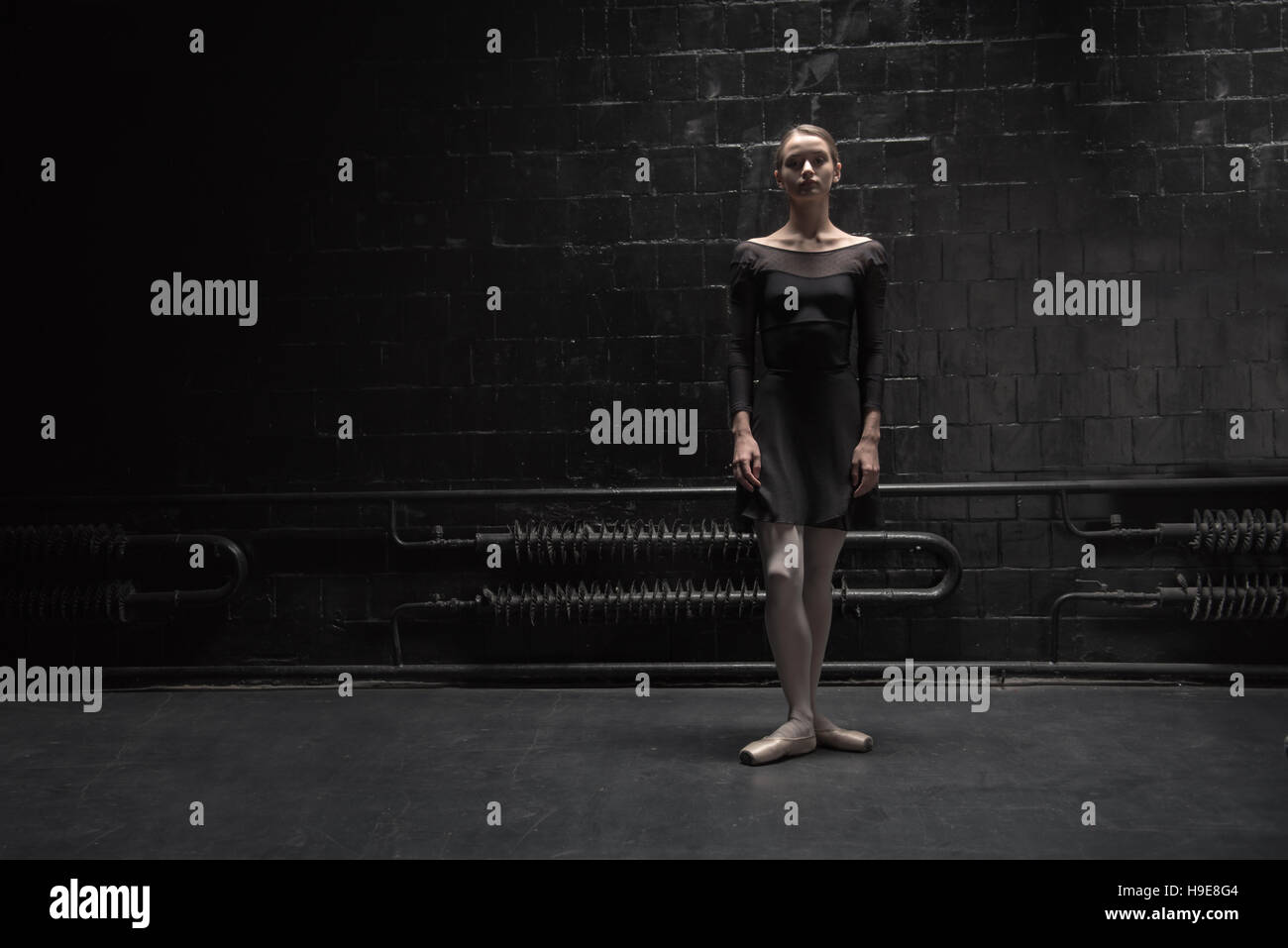 Steady young dancer standing near the dark wall Stock Photo - Alamy