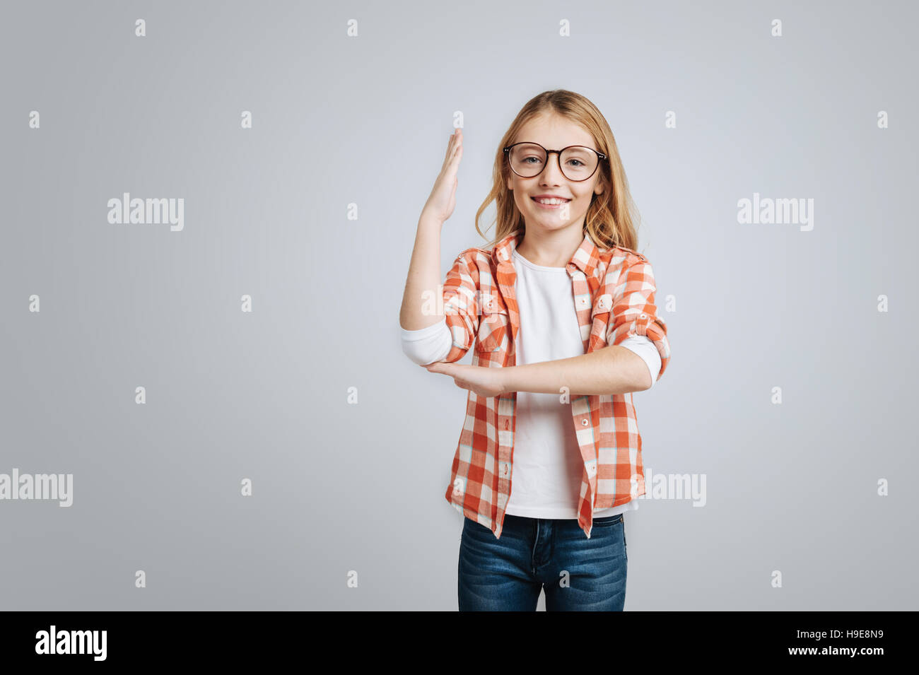 Joyful little girl raising her hand Stock Photo - Alamy