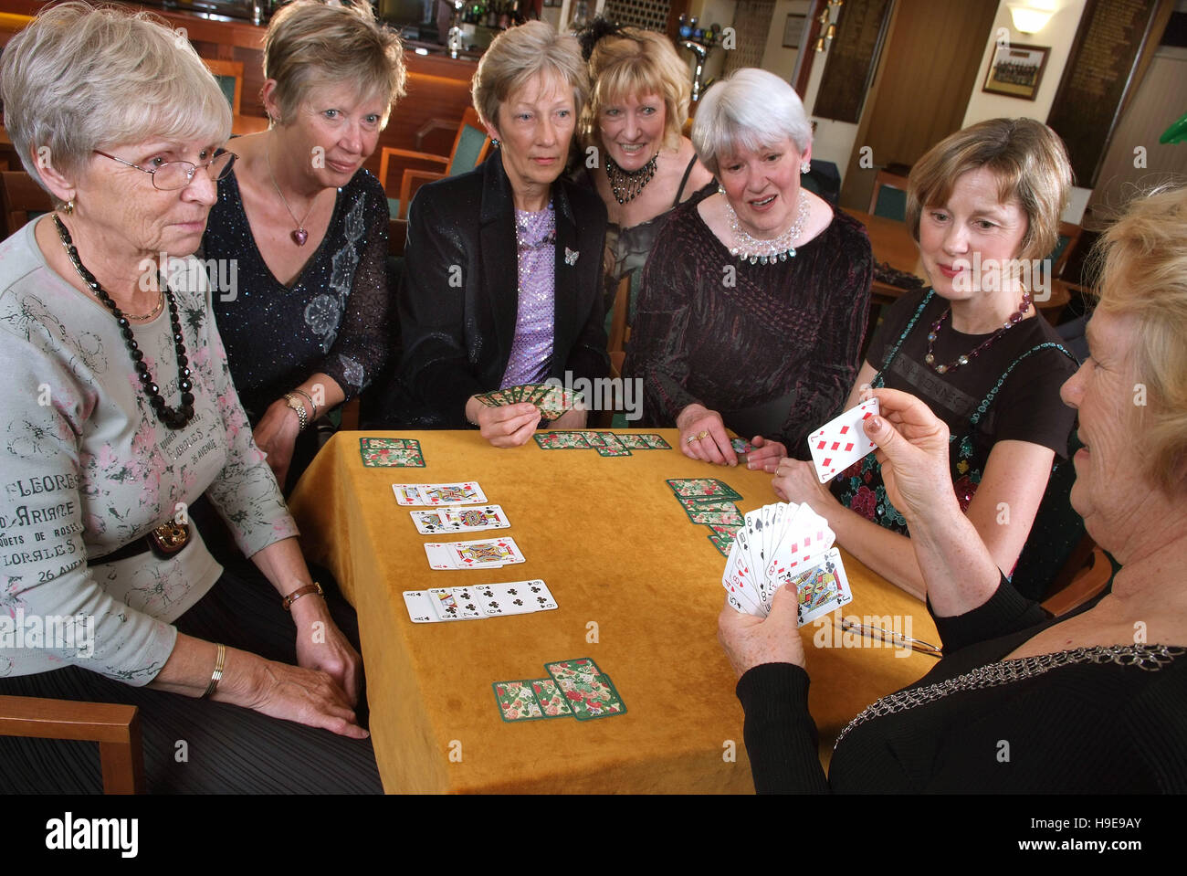 A group of seven women bridge players, sitting around a single table ...