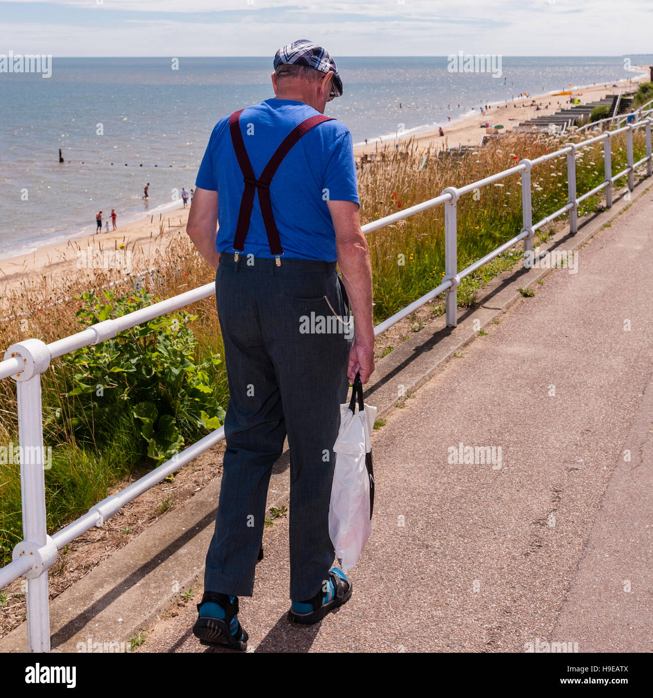 A man walking along the top of the seafront in Southwold , Suffolk ...