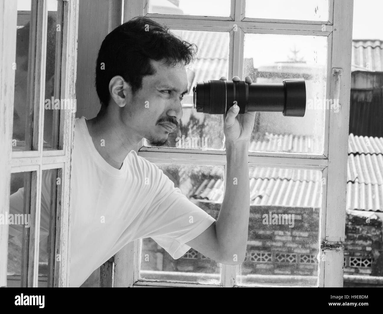 Man looking out through a window using a telephoto lens. Humorous ...