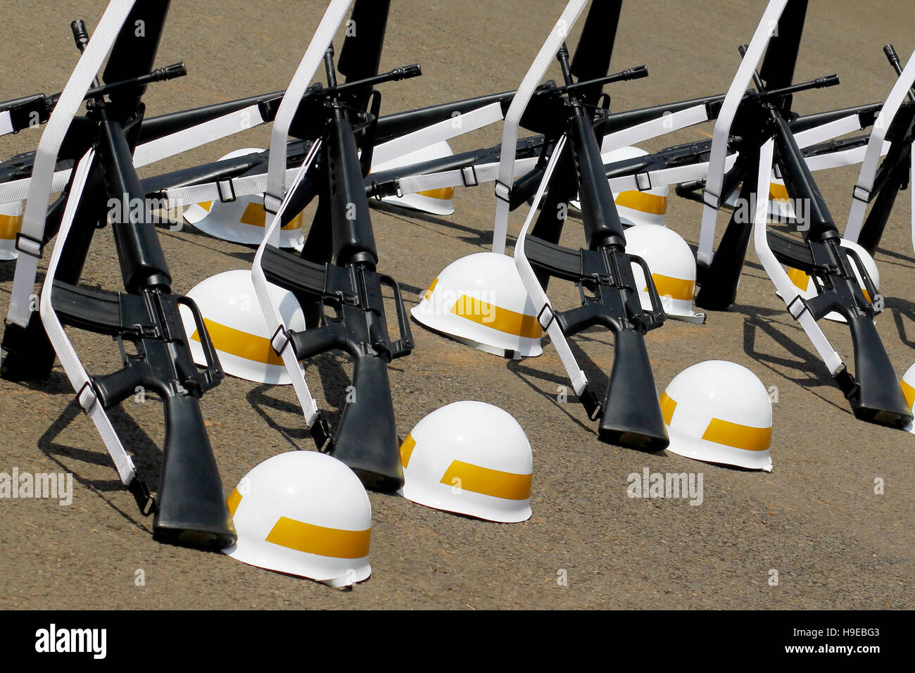 Formation of assault rifles and yellow striped helmets laid on the ...