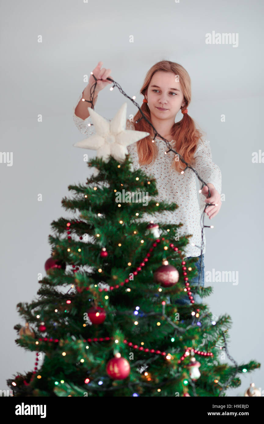 Young girl decorating Christmas tree with lights at home Stock Photo ...