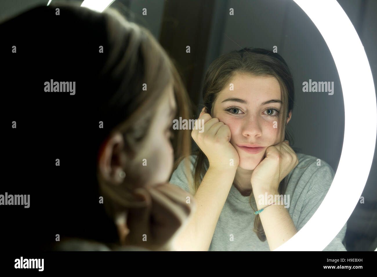 Portrait of teenage looking in a mirror, with the sad and serious face ...