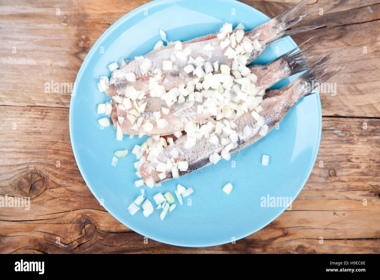 Traditional Dutch raw herring with onions on plate on wooden background ...