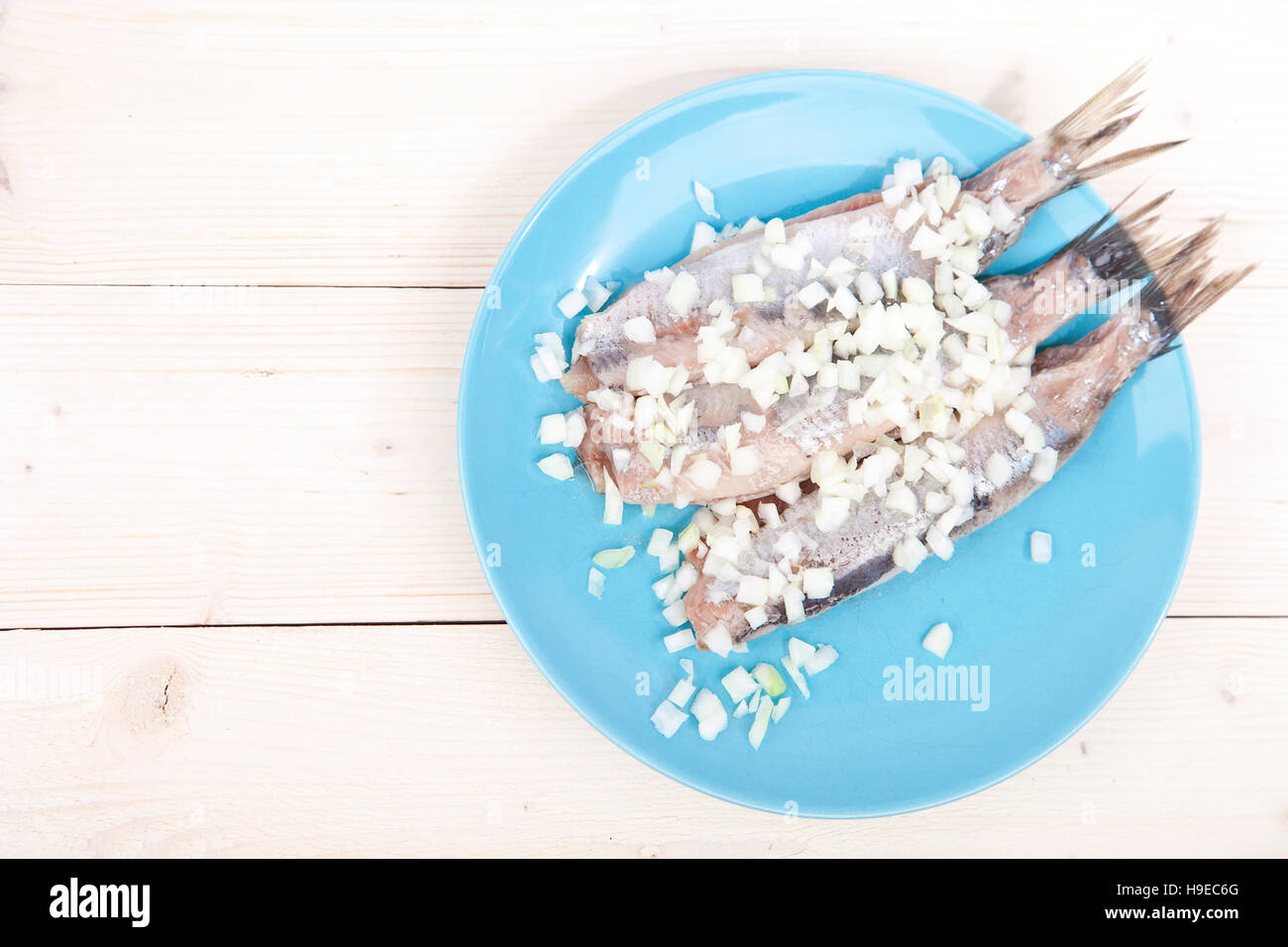 Traditional Dutch raw herring with onions on plate on wooden background ...