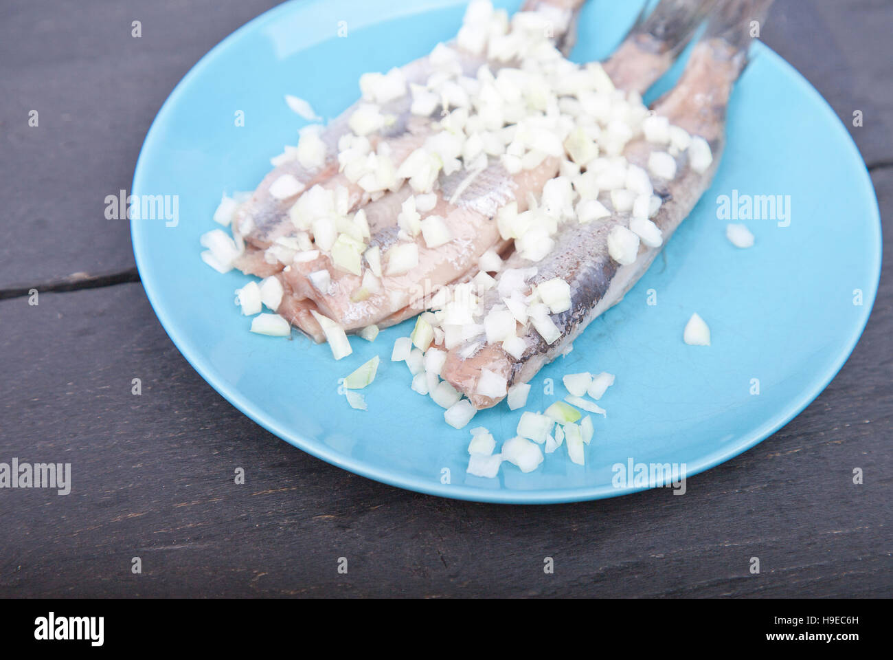Traditional Dutch raw herring with onions on plate on wooden background ...