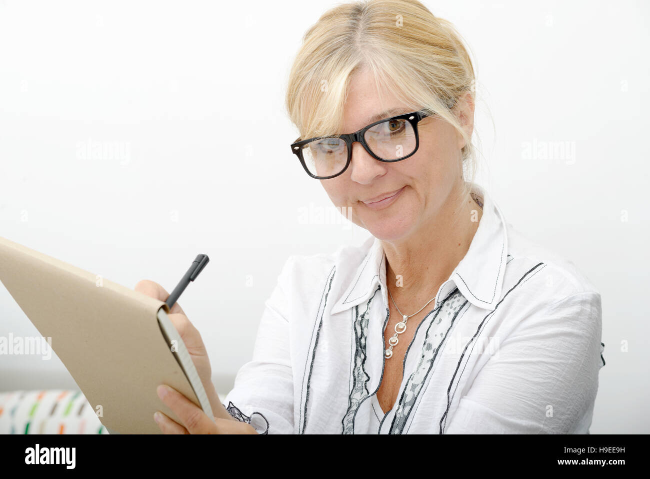 beautiful mature woman writing on a notebook with eyeglasses Stock ...