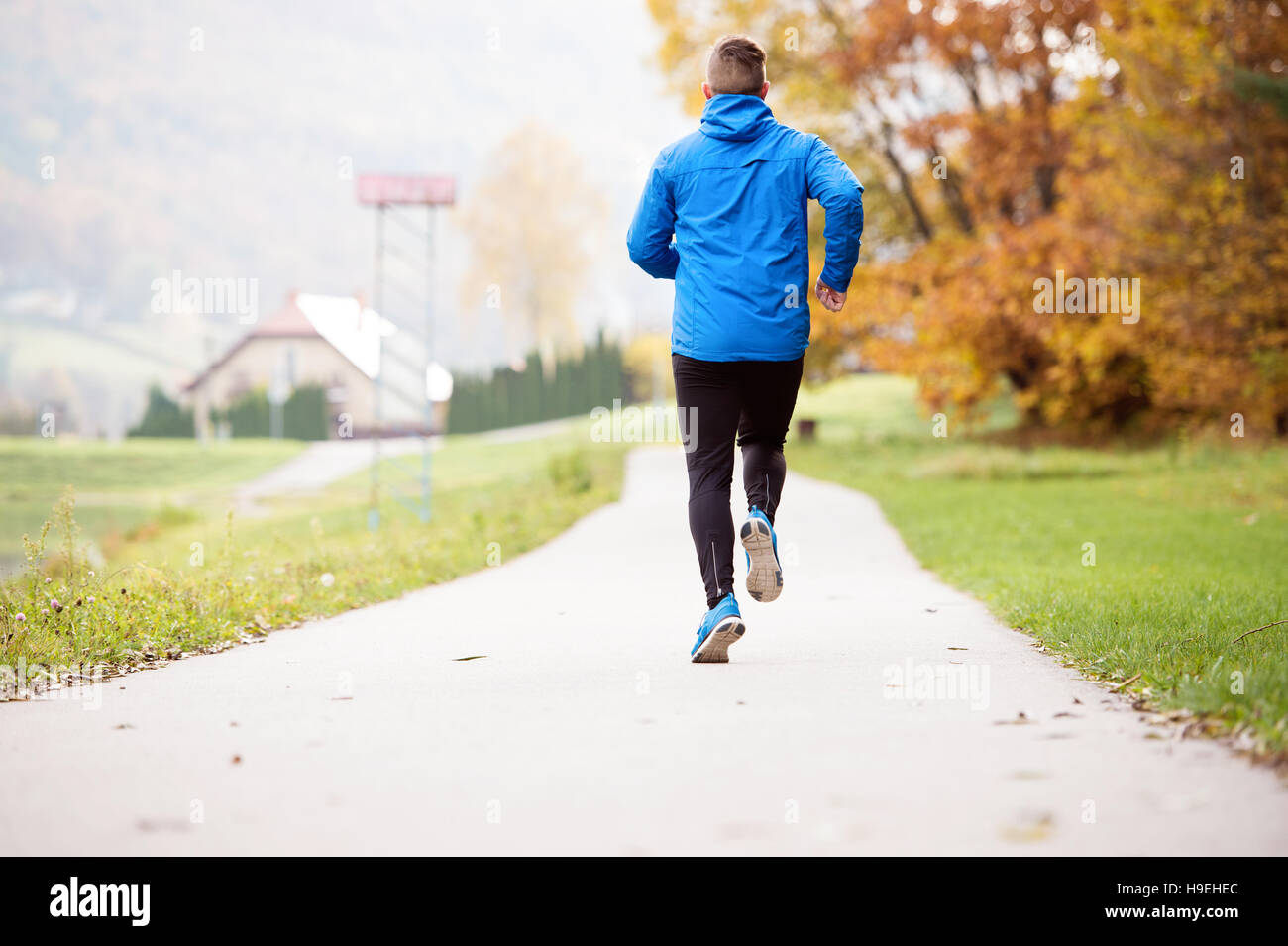 Athlete at the lake running on concrete path, rear view Stock Photo - Alamy