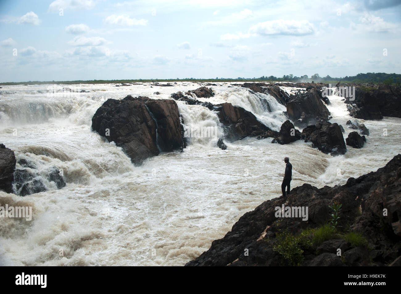 A man overlooking the Sopheakmith Falls, tumultuous rapids which form ...