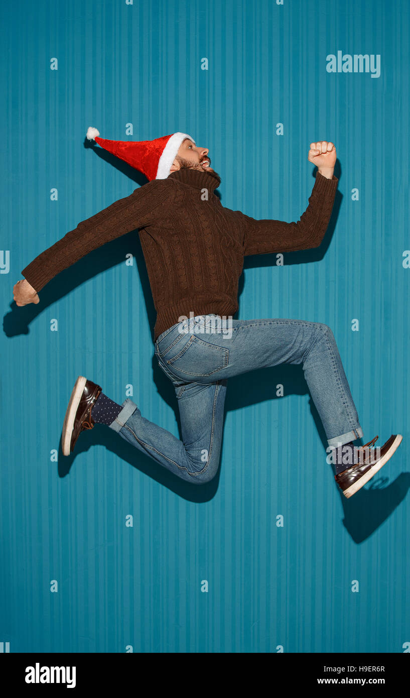 The running christmas man wearing a santa hat on the blue studio ...