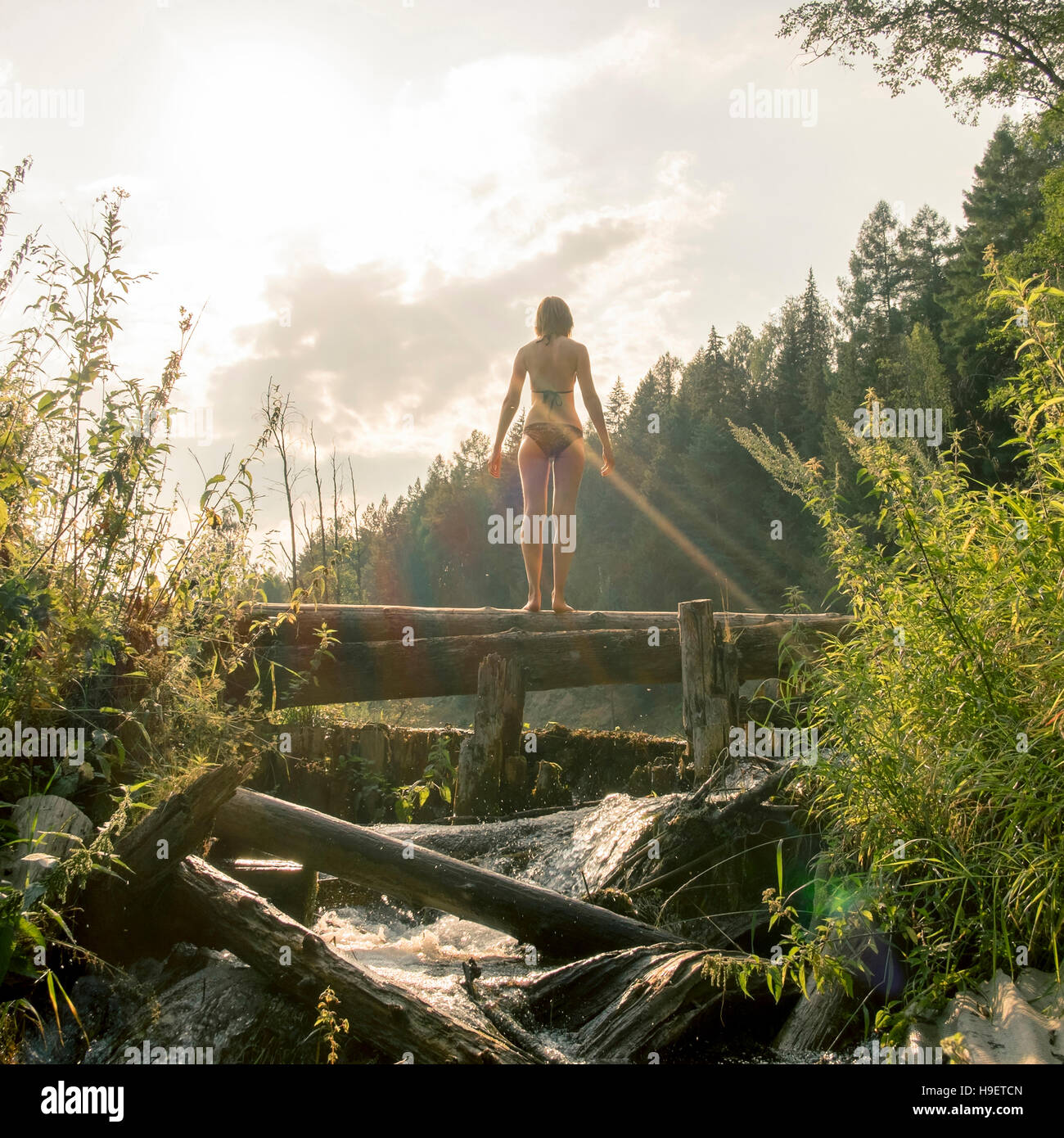 Caucasian woman standing on log over waterfalls Stock Photo - Alamy