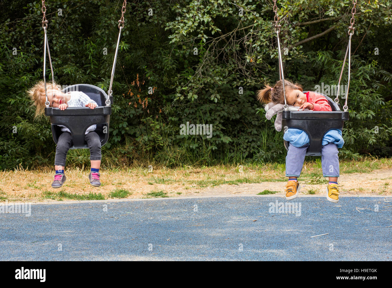 Girls sitting in still swings Stock Photo - Alamy