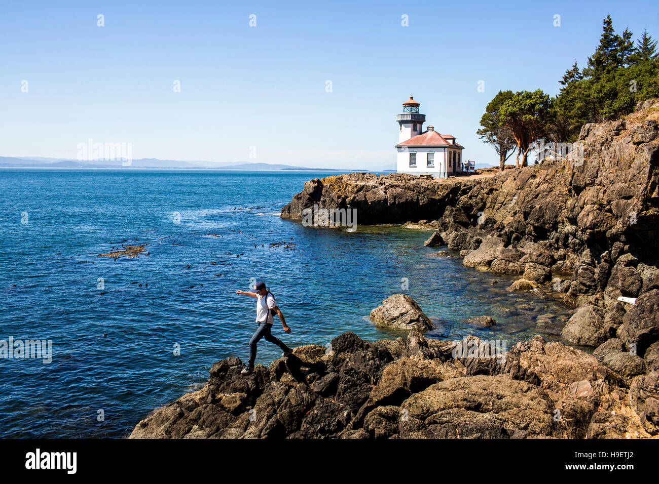 Caucasian man walking on rocks near lighthouse Stock Photo - Alamy