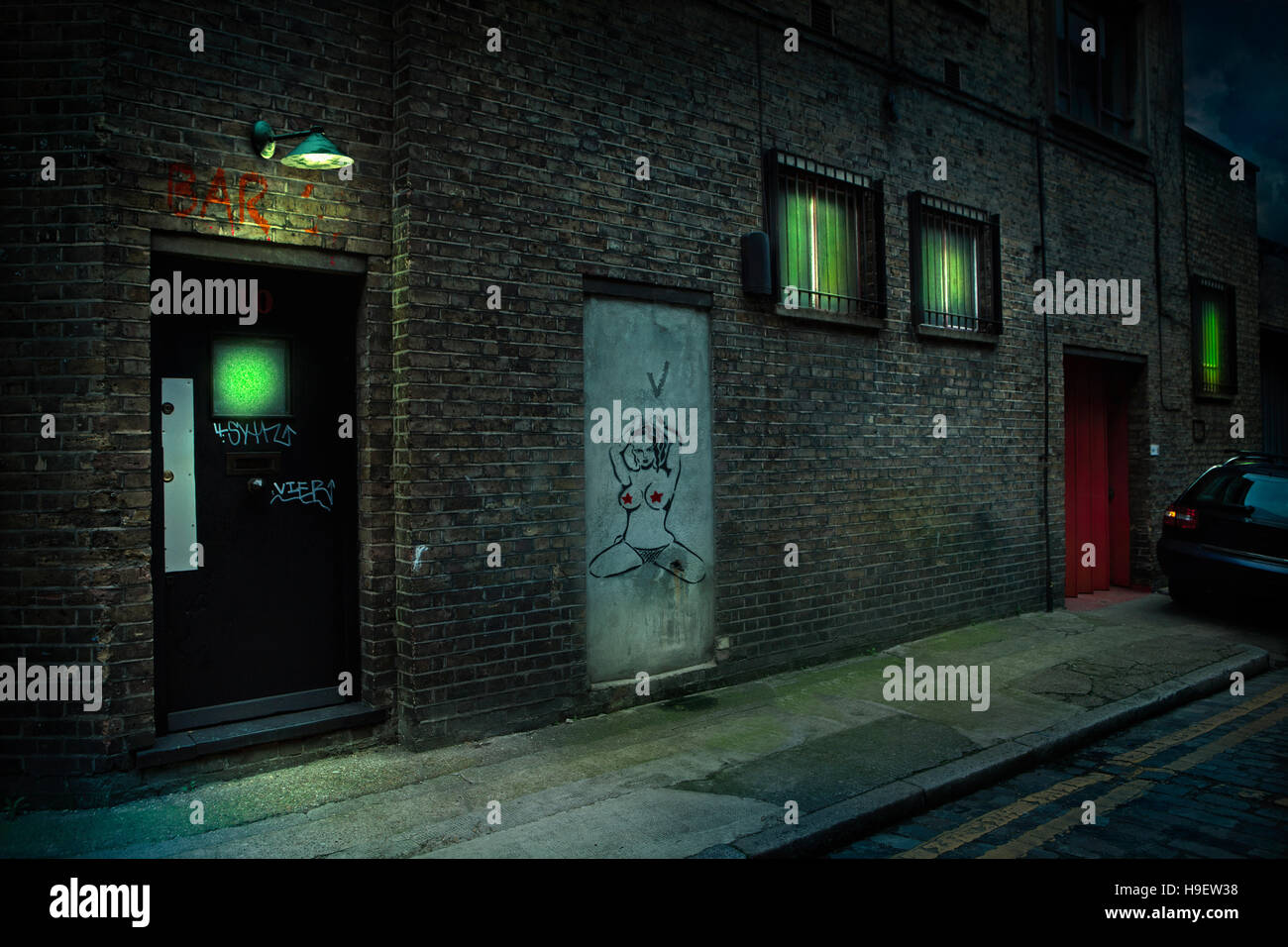 Graffiti on alley doors in city at night Stock Photo - Alamy