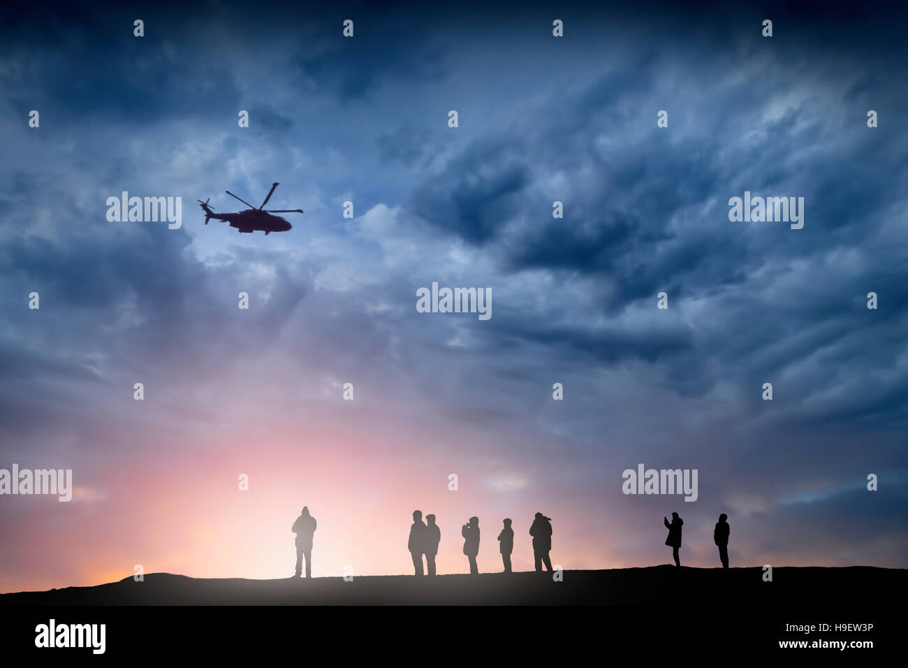 Silhouette of helicopter flying over people at sunset Stock Photo - Alamy