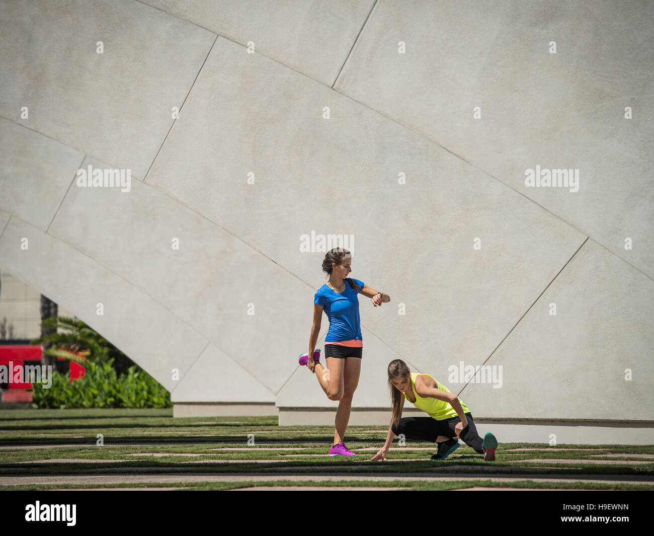 Caucasian women stretching legs near architecture Stock Photo - Alamy