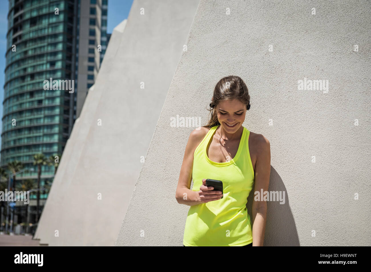 Caucasian woman leaning on wall texting on cell phone Stock Photo - Alamy