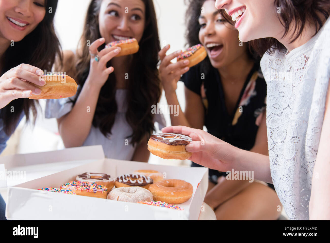 Smiling women eating donuts Stock Photo - Alamy