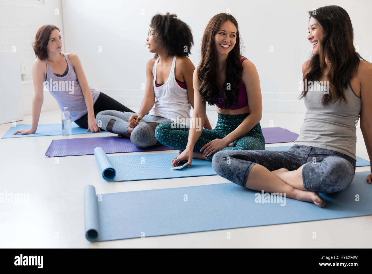 Smiling women sitting on exercise mats Stock Photo - Alamy