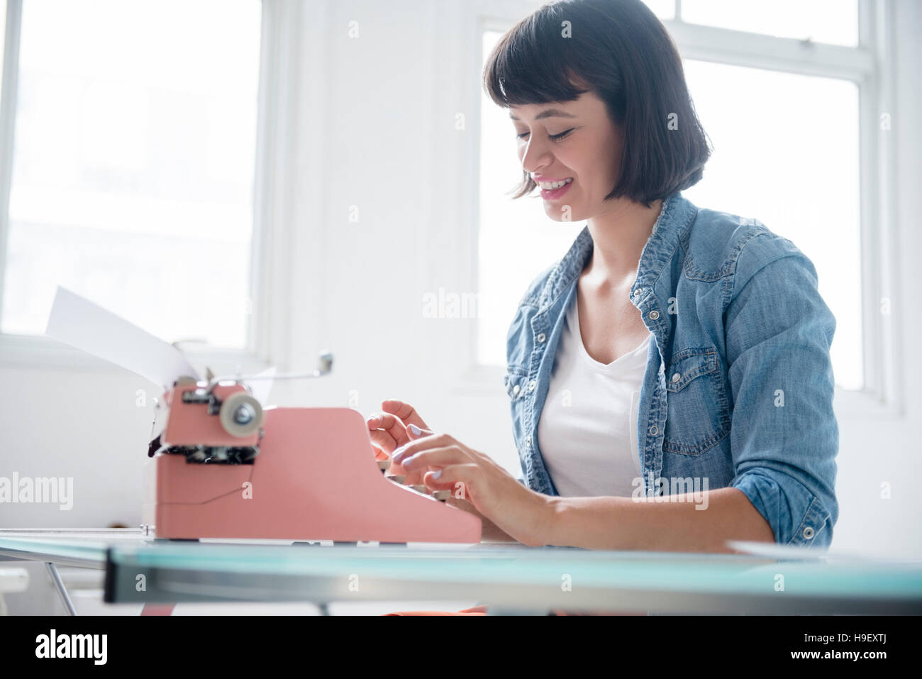 Hispanic woman typing on pink typewriter Stock Photo - Alamy